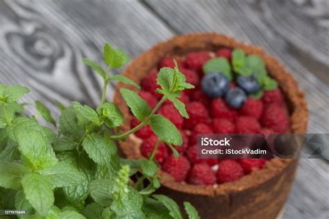 크림 치즈를 곁들인 초콜릿 케이크를 굽지 않습니다 라즈베리 블루베리 민트 잎으로 장식되어 있습니다 근처에는 성장하는 민트냄비가 있습니다 소나무 보드의 표면에 검은 색과