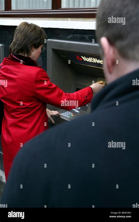 ATM Cash Machine Scam Man Watches A Woman Inserting Her Card Into The Machine United Kingdom