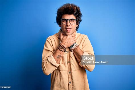 고립 된 파란색 배경 위에 서있는 캐주얼 셔츠를 입은 젊은 잘생긴 남자는 고통스러운 목졸림 때문에 외치고 질식합니다 건강 문제 질식 과 자살 개념 건강관리와 의술에 대한