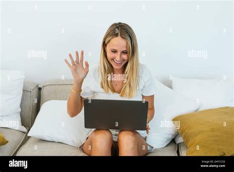 Positive Female Waving Hand While Having Video Chat On Modern Laptop On