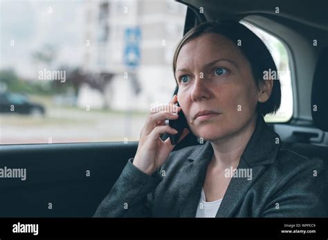 Surprised Businesswoman Talking On Mobile Phone On Car Back Seat