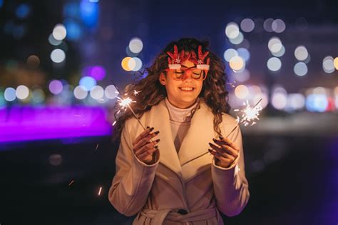 도심에서 두 명의 스파클러를 들고 새해 복 많이 받으며 안경을 쓴 미소 짓는 젊은 여성 12월 31일에 대한 스톡 사진 및 기타 이미지 12월 31일 18 19세