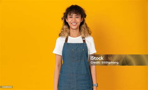 쾌활한 아름다운 아시아 여성의 스튜디오 샷은 앞치마를 착용하고 오렌지색 배경에 미소를 지으며 서 있습니다 여자에 대한 스톡 사진 및 기타 이미지 Istock