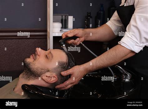 Professional Hairdresser Washing Mans Hair At Sink In Barbershop Stock