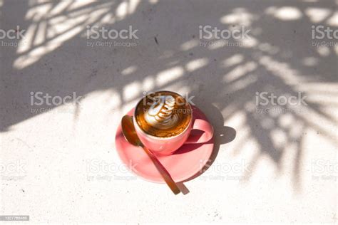 열대 야자수 그림자와 흰색 배경에 황금 숟가락 접시에 라떼 아트와 카푸치노의 핑크 컵 그림자에 초점 맞추기에 대한 스톡 사진 및