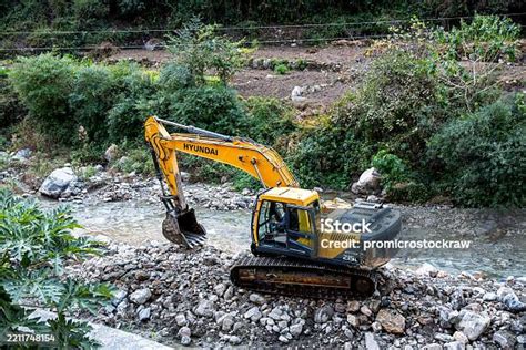 궤도형 대형 굴착기가 강바닥에서 활발하게 작업하며 암석을 제거하고 있습니다 이 기계는 강의 흐름을 유지하는 데 중요한 역할을 합니다 기계류에 대한 스톡 사진 및 기타 이미지