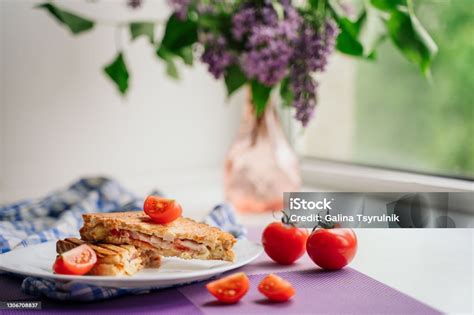 봄 또는 여름 아침 식사 부엌의 흰색 접시에 햄 치즈를 토스트 음식의 아름다운 서빙 테이블에 신선한 라일락 꽃 체리 토마토