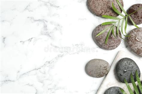 Spa Stones With Water Drops And Green Leaves On White Marble Table
