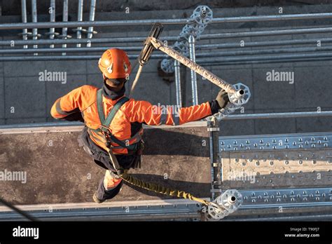 Worker Placing Scaffolding While He Is Fastened To A Safety Cable The Worker Is Dressed In
