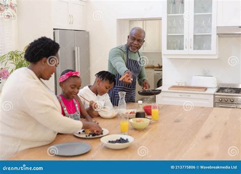 Abuelos Afroamericanos Cocinando Con Nieto Y Nieta Sonrientes En La Cocina Foto De Archivo