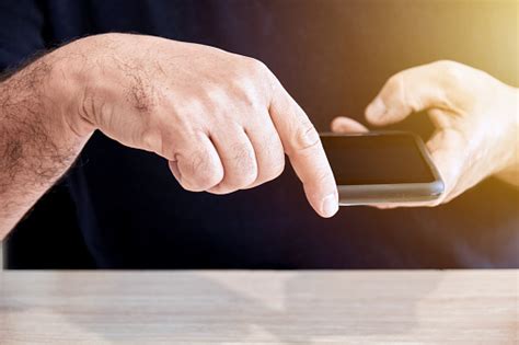 사업가는 휴대 전화를 손에 들고 손가락이 복사 공간이있는 나무 사무실 책상을 가리킵니다 기업 재무와 산업에 대한 스톡 사진 및