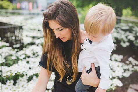 Young Cool Mom Holding Her Son While Picking Flowers By Stocksy