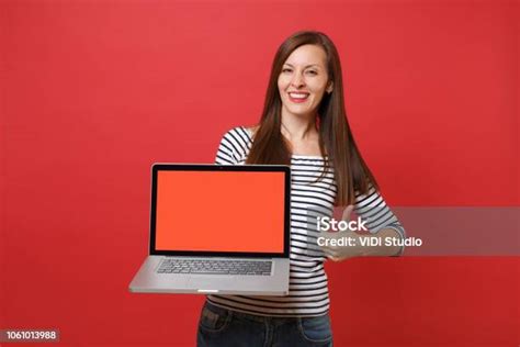 아름 다운 젊은 여자 엄지를 보여주는 밝은 빨간 벽 배경에 고립 된 빈 블랙 빈 화면으로 노트북 Pc 컴퓨터를 들고 사람들이