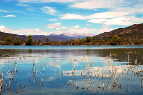 Um lago montanhas ao fundo e um céu azul nuvens ao fundo