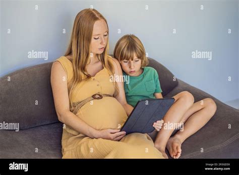 la mère et le fils enceintes regardent la tablette Lire un livre regarder un dessin animé ou