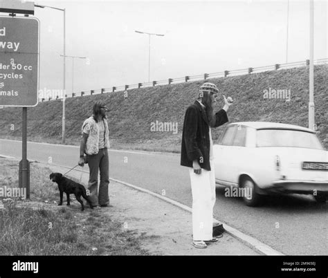 Two Hippy Hitch Hikers Thumbing A Lift But Will Anyone Stop For Them