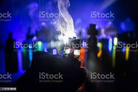 Vape 개념입니다 전자 담배 Vape 폭발 어두운 배경에 연기 구름과 Vape 액체 병 조명 효과 Vape 광고로 유용 합니다