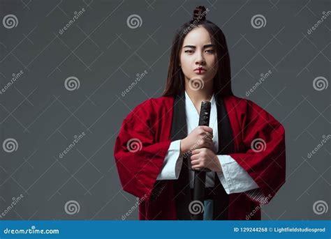 Asian Woman In Kimono Holding Katana Sword And Looking At Camera Stock