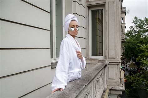 목욕 가운을 입은 여성과 발코니에서 아침을 즐기는 머리 수건을 감싸고 아름다움이 있는 눈 아래 패치 치료와 커피를 마시는 가정 생활에 대한 스톡 사진 및 기타 이미지