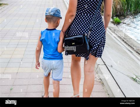 Mom And Son Are Walking Around The Park In The Hand Back View Mother In A Dress Stock Photo