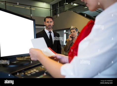 Close Up Of Female Staff Checking Boarding Pass With Passenger In