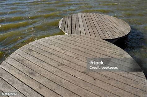 나무 판자로 만든 떠있는 산책로 기둥의 좁은 곡선 길은 호수 물 위 바닥으로 구동된다 난간이 없습니다 개별 원형 보드로 만든 더 많은 디자인 보도 가을 방파제 0명에 대한
