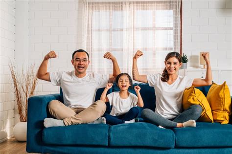 Father Mother And Daughter Doing Exercise In Living Room At Home Stock