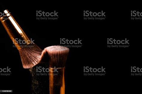 검은 색 배경에 제품 플라잉 컬러 파우더와 두 메이크업 브러쉬 미니멀 한 블랙으로 메이크업하는 매력의 개념 0명에 대한 스톡