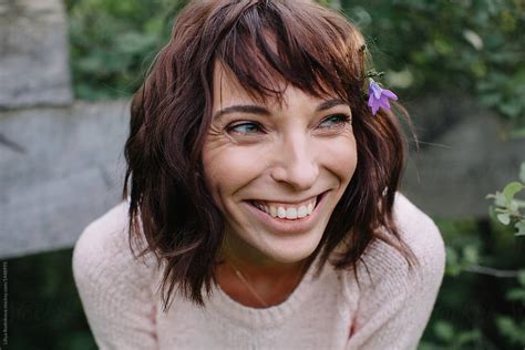Emotive Portrait Of Extremely Happy Woman With Little Violet Flower In Her Hair By Stocksy