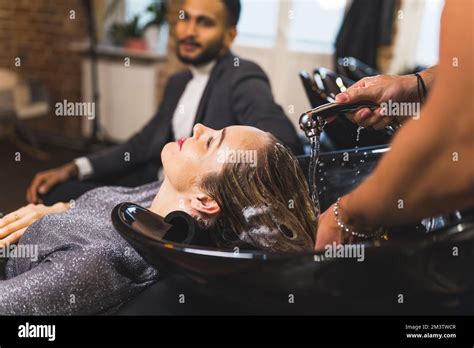 Hairdresser Rinsing Hair Of Female Customer With Water After Using