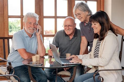 Grupo Feliz De Idosos Caucasianos Usando Laptop E Celular Sentado à