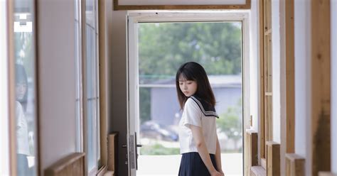 흰색 긴팔 셔츠와 검은 치마를 입은 여자가 유리창 옆에 서 있다 사진 Unsplash의 무료 의류 이미지