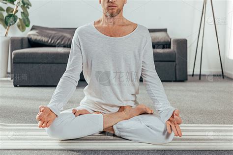 一名男子穿着运动服坐在瑜伽垫上沉思