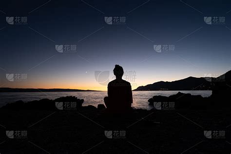 日落时天空背景上女孩的剪影。瑜伽和冥想。休息和放松的地方。夏天的风景。地中海。