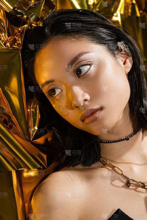 迷人的亚洲年轻女子肖像，湿透了的短发，紧靠着闪亮的黄色背景，模特，回头看，皱巴巴的金箔，亚洲美女，自