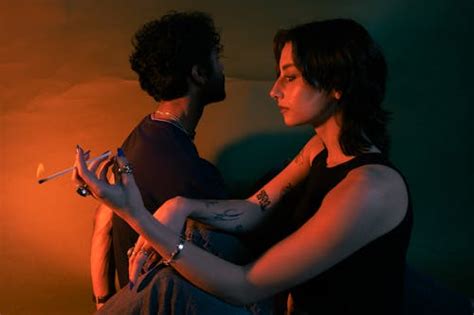 긴 머리 담배를 피우는 담배를 피우다 문신 앉아 있는 여성 염색 한 머리카락 잡고 있는 전자 담배 포즈를 취하는에 관한 무료 스톡 사진