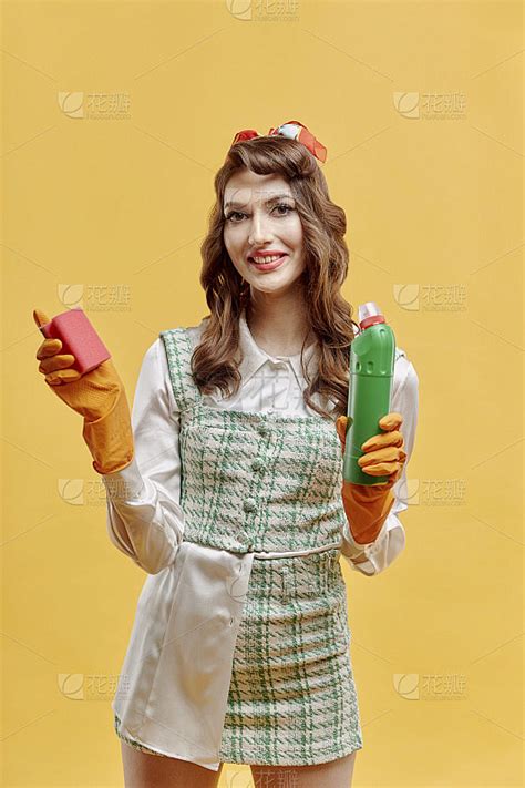 一个清洁女工拿着一瓶家用化学品和一块海绵。