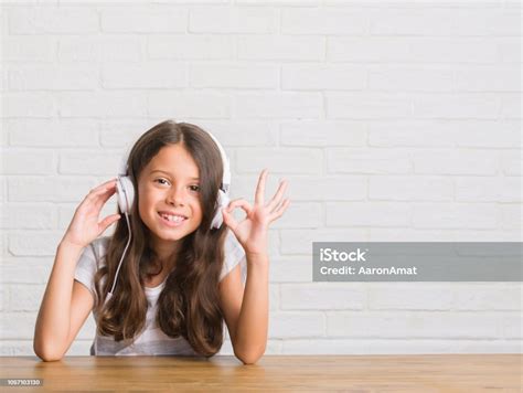 젊은 라틴계 아이 손가락 우수한 기호 확인 서명 하 고 헤드폰을 착용 하는 테이블에 앉아 개념에 대한 스톡 사진 및 기타 이미지