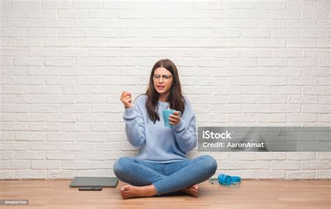 흰색 벽돌 벽 마시는 커피 화가 바닥에 미친과 소리 제기 손으로 분노와 좌절된 함 분노 개념 앉아 젊은 갈색 머리 여자 갈색