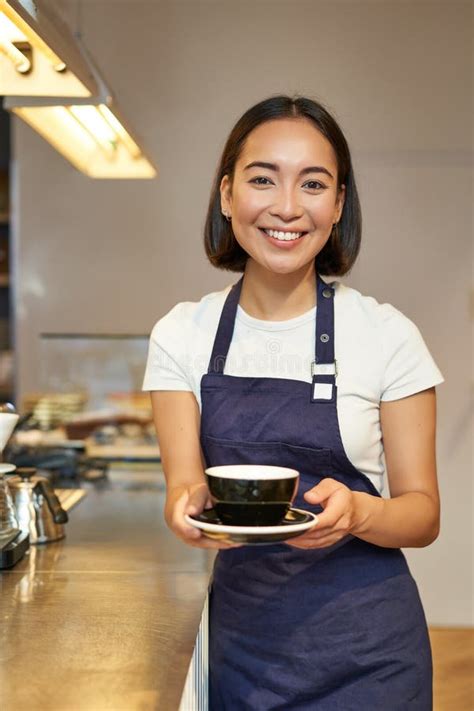 Smiling Beautiful Asian Girl Barista Working In Cafe Holding Cup Of