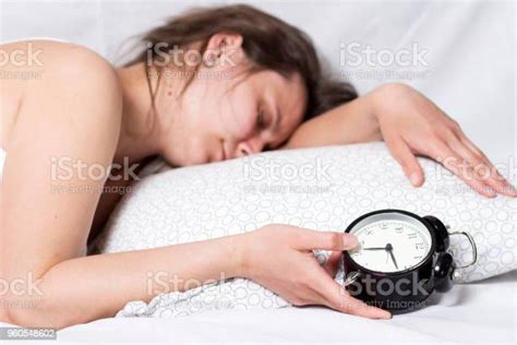 잠자는 여 자가 알람 벨에서 일어나 하지 않을 수 있습니다 여자는 침대에서 자 고 알람 시계를 그녀의 손에 들고 여자 없는 이른