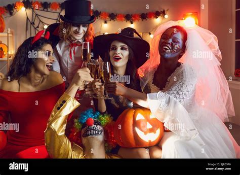 Group Of Happy Young People In Spooky Costumes Drinking Champagne At