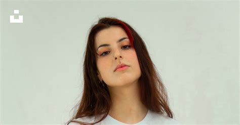 Mujer Con Camiseta Blanca De Cuello Redondo Sentada En Una Cama Blanca