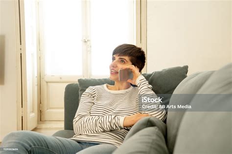 스마트 전화 얘기 하 고 인터넷 및 소셜 미디어 기술 라이프 스타일 통신 및 사람들 개념에 집에서 소파에 앉아 메시지 확인에 행복 꽤 젊은 백인 여자 검색에 대한 스톡 사진