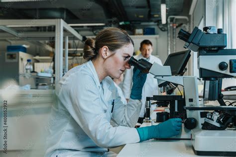 Young Woman Analyzing Human Brain Microscope Slide Under Microscope