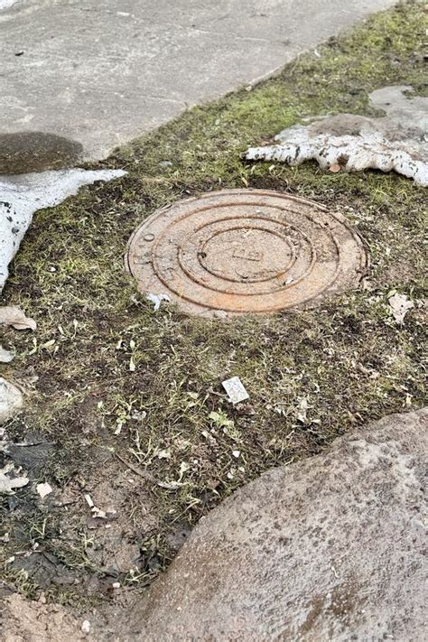 A Rusty Iron Hatch With A Pattern Is Located Next To A Dry Grass
