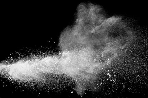 黒い背景に白い粉の爆発雲の奇妙な形。白い塵の粒子が飛び散る。 プレミアム写真