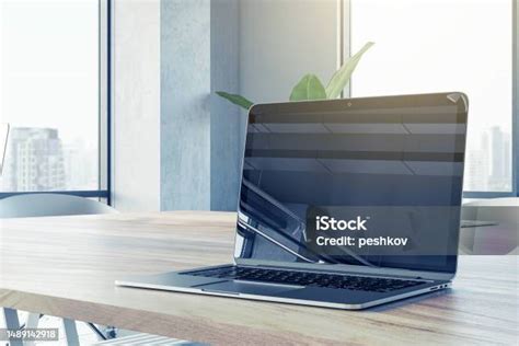 빈 화면이 있는 목조 사무실 책상의 근접 측면 보기 햇볕이 잘 드는 실내에서 도시 전망을 배경으로 한 큰 창문 모형 웹 디자인 및 프로젝트 프레젠테이션 개념입니다 3d