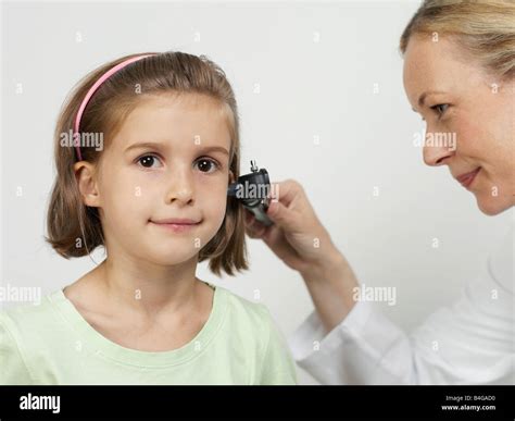 A Female Pediatrician Using An Otoscope To Exam A Girls Ear Stock