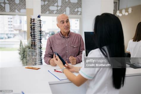 Mature Man Purchasing Medicine At Pharmacy Listening To Pharmacist High